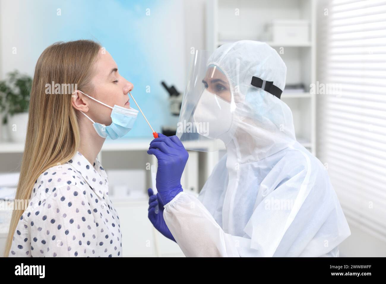 Laboratory testing. Doctor in uniform taking sample from patient's nose ...