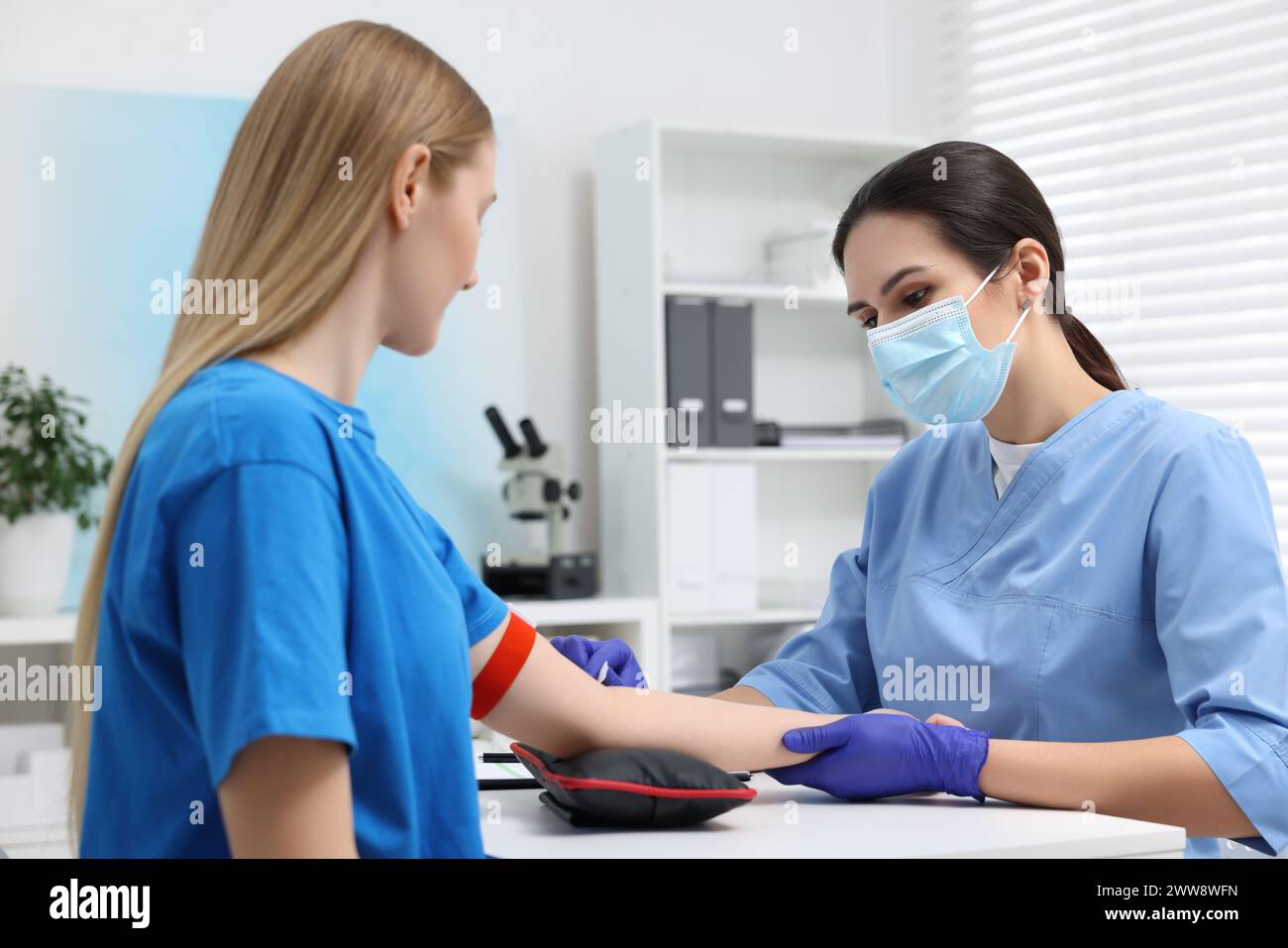 Laboratory testing. Doctor taking blood sample from patient at white ...