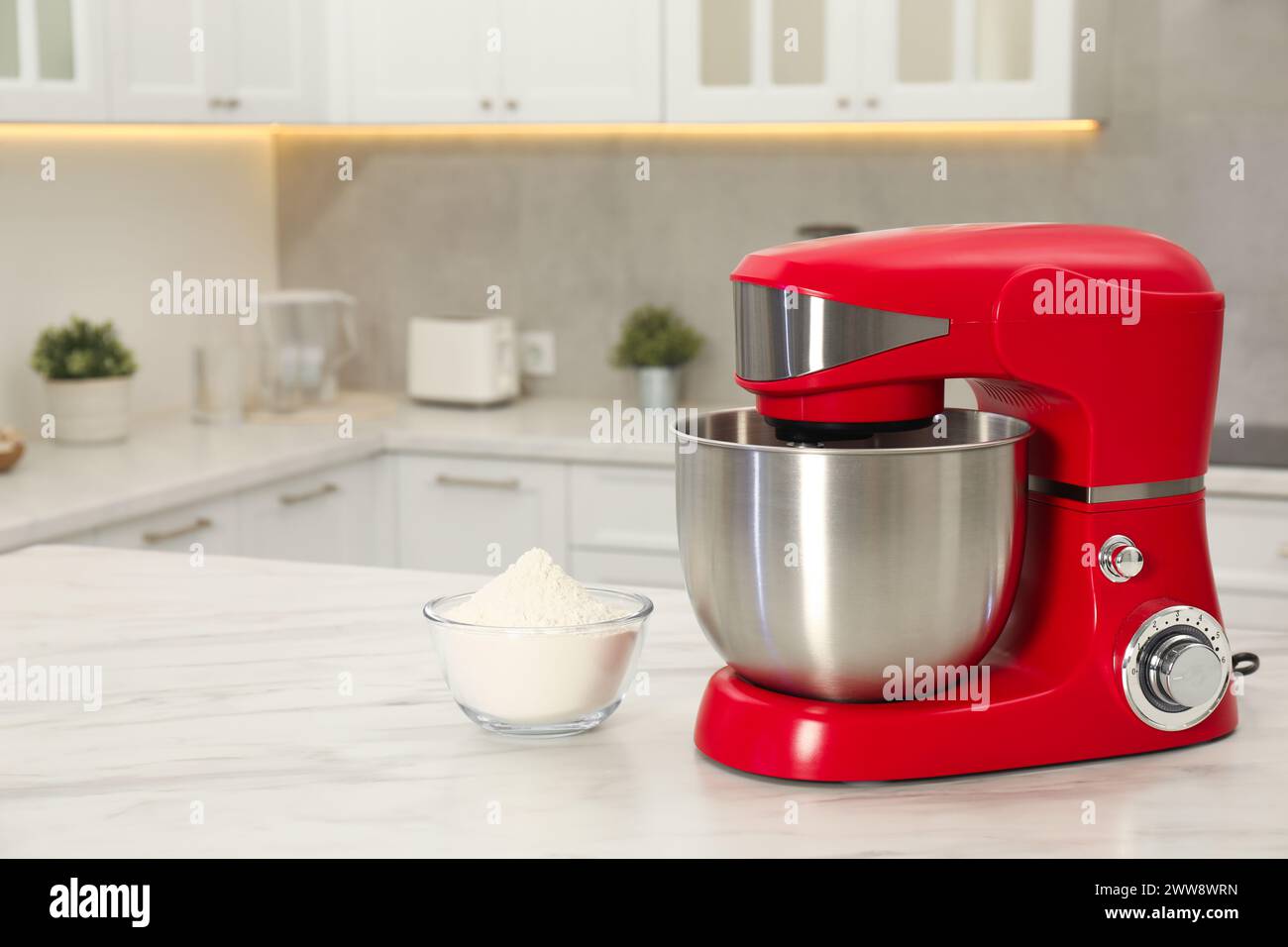 Modern red stand mixer and bowl with flour on white marble table in ...