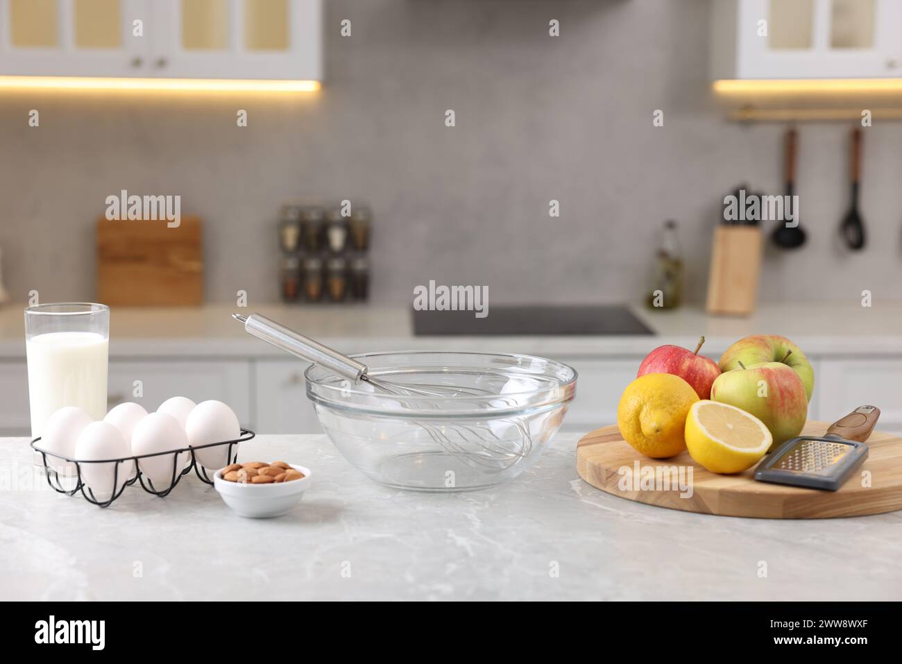 Metal whisk, bowl, grater and different products on gray marble table ...