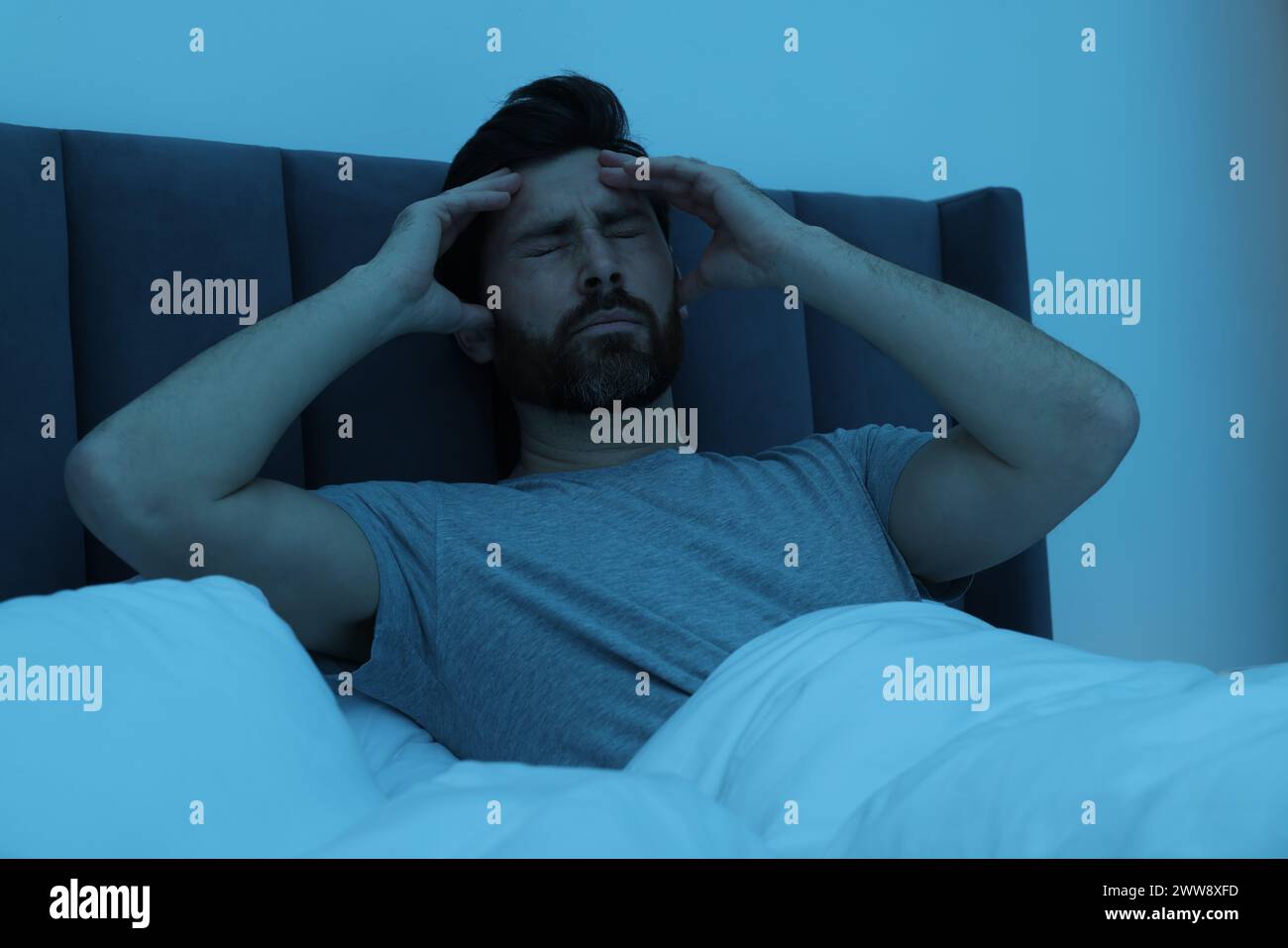 Man suffering from headache in bed at night Stock Photo - Alamy