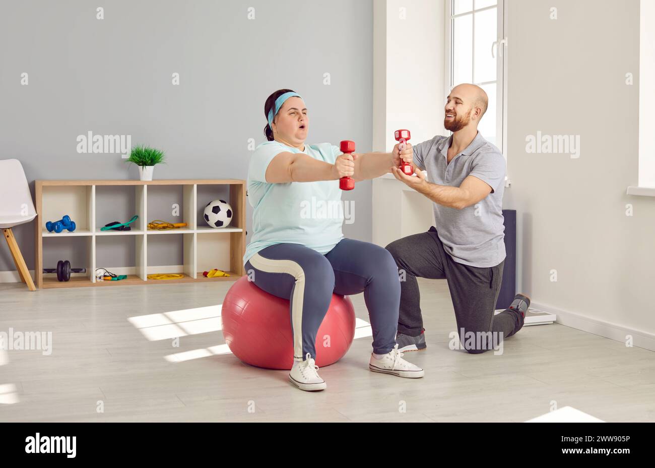 Plus size, fat woman training with dumbbells under guidance of personal ...