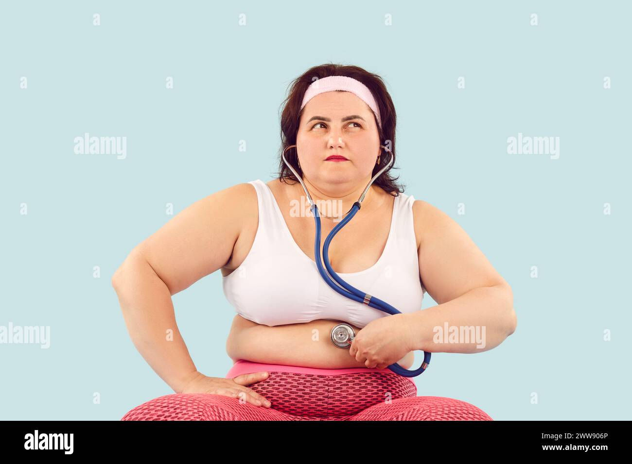 Young woman with obesity and digestion problems holds stethoscope on ...