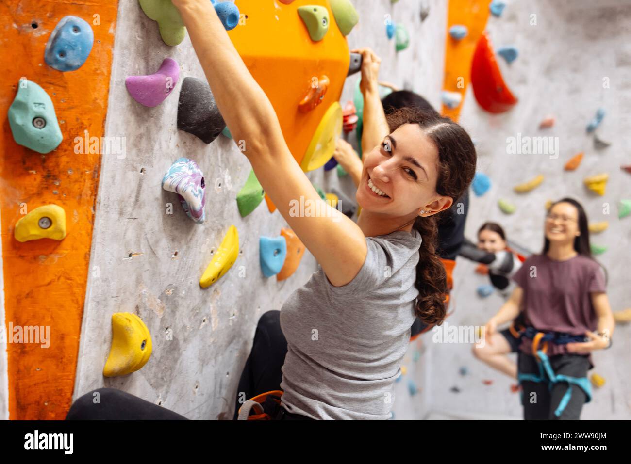 A group of multiracial women doing rock climbing in the gym. Attractive ...