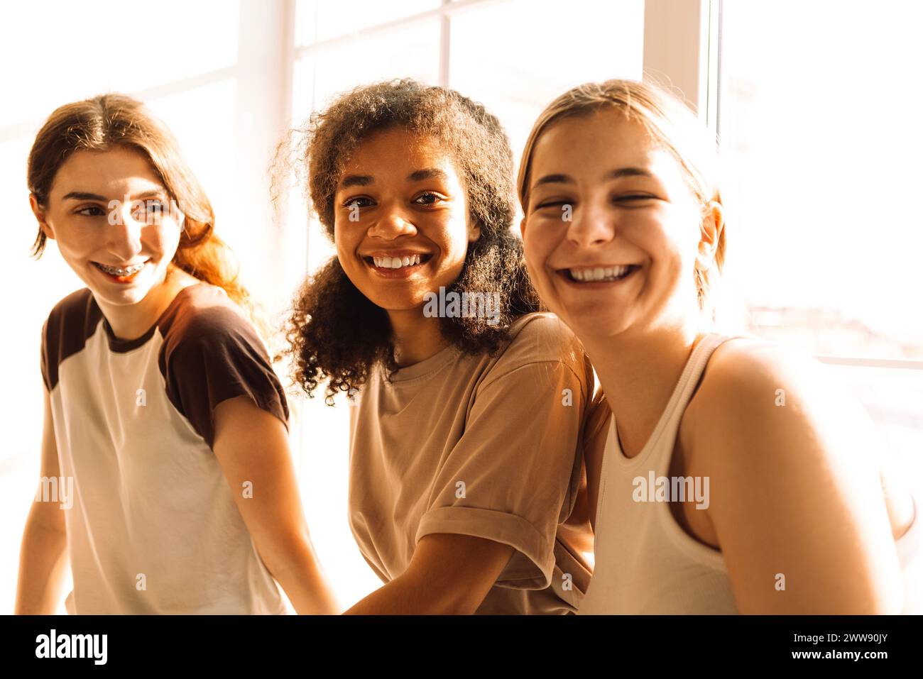 Happy cute girls of different races are laughing and chatting. Charming friends smile and have ...