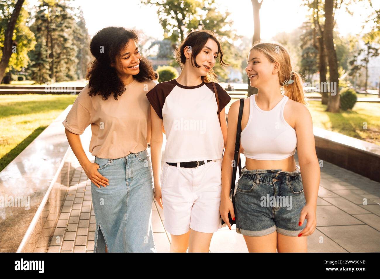 Happy cute girls of different races are chatting and walking in the ...