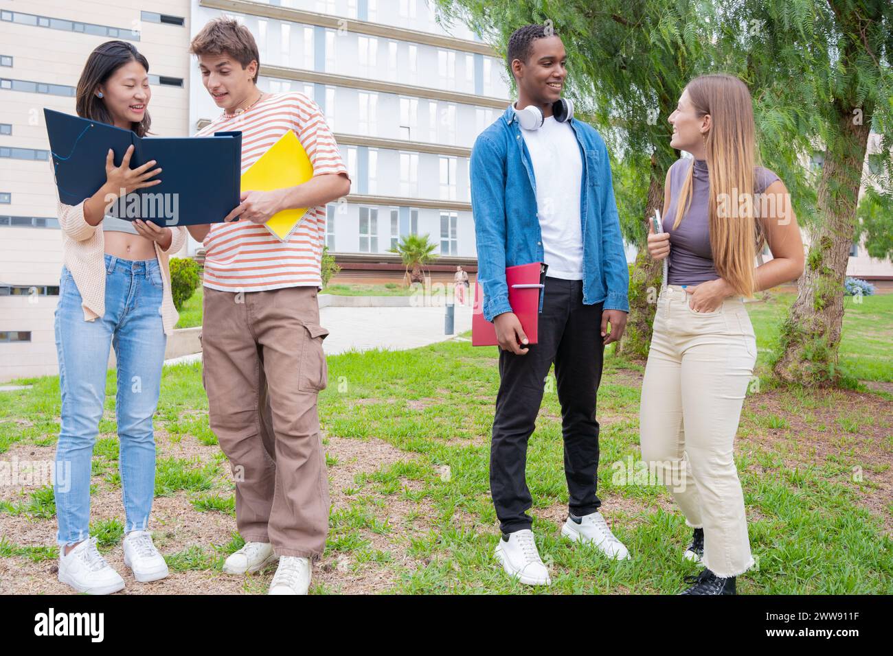 Group Of Four College Friends Smiling Looking At Notes, Talking And ...