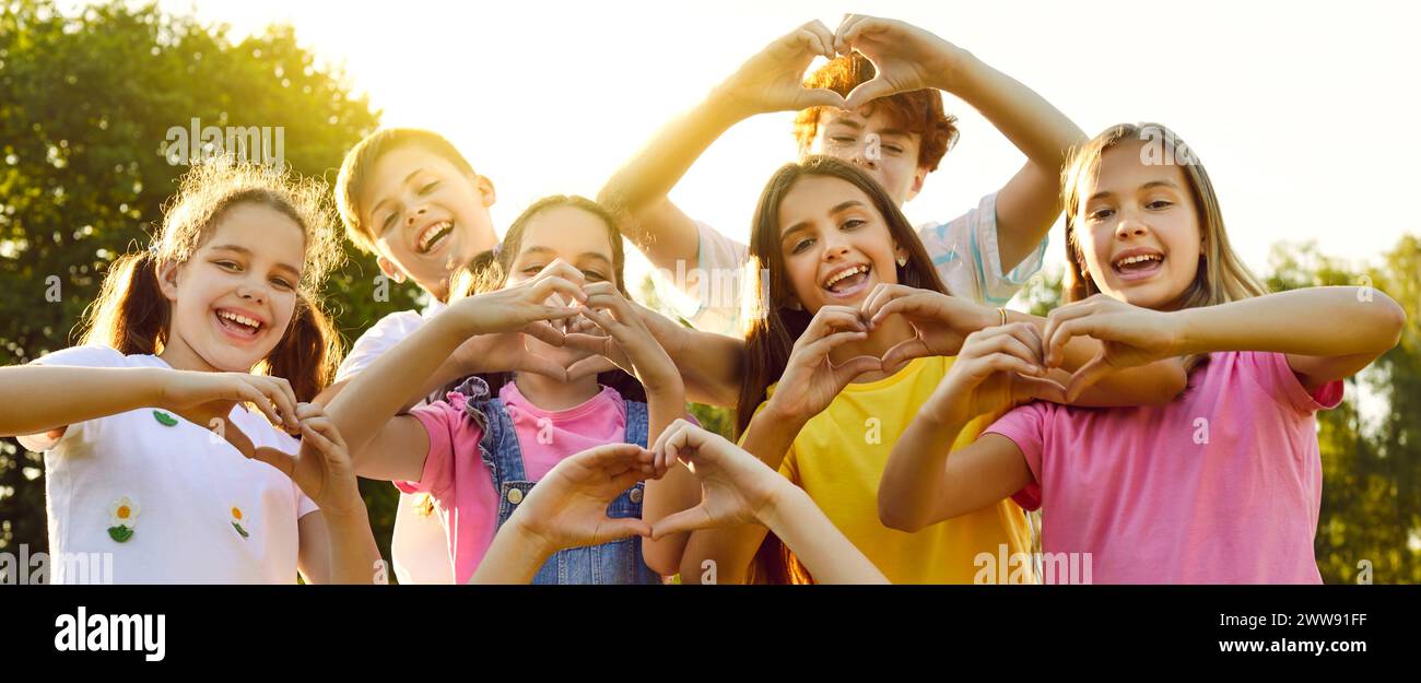 Portrait of a happy smiling children friends making heart sign by hands ...