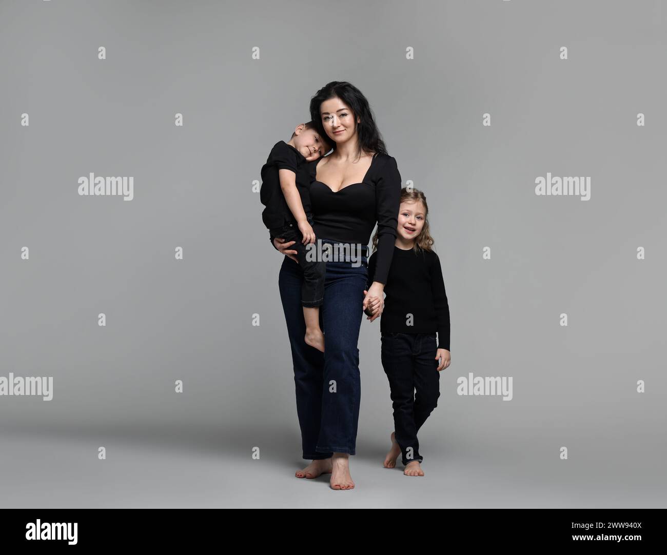 Little children with their mother on grey background Stock Photo - Alamy