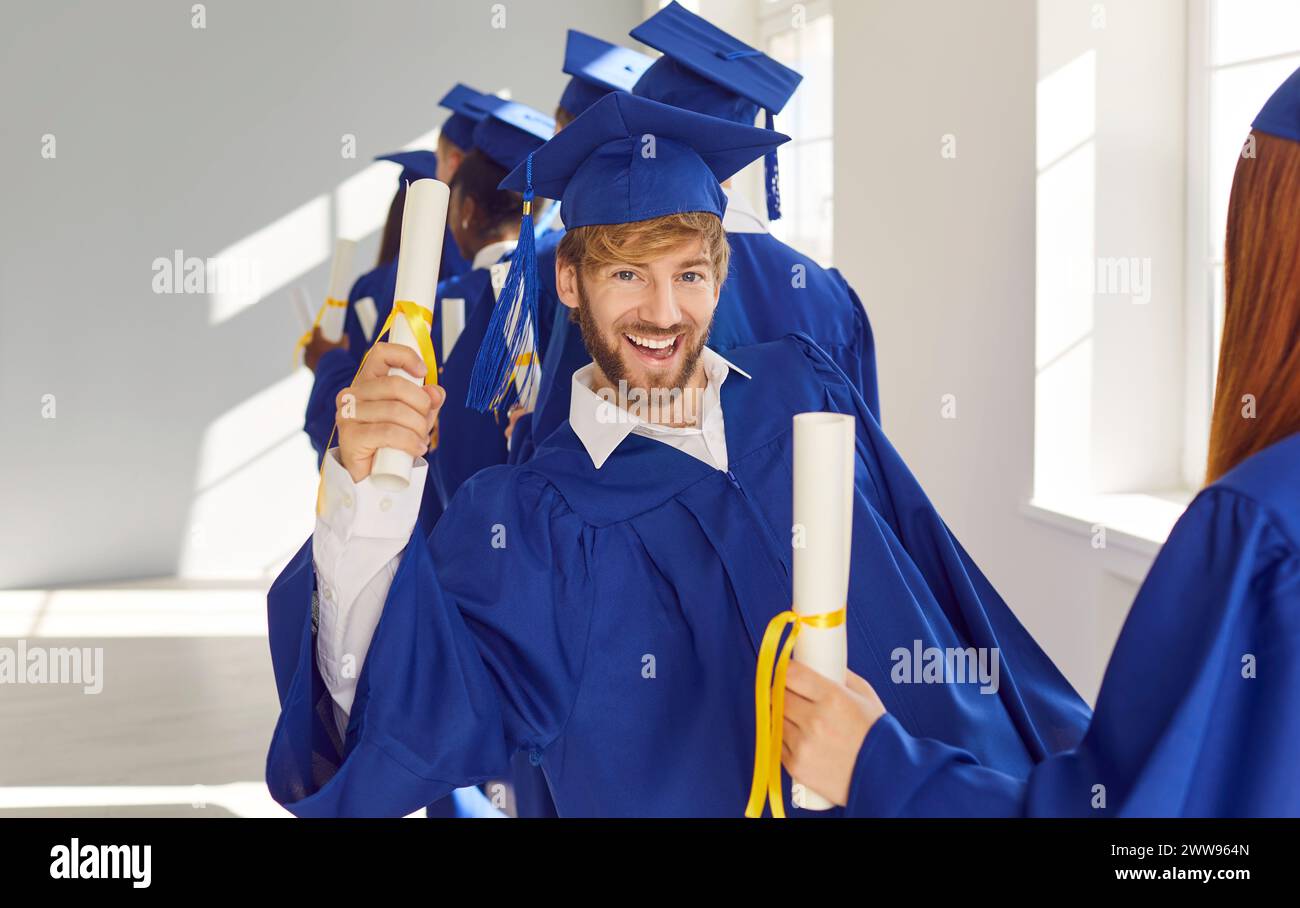 Graduate Man in Cap and Gown Holds Diploma Amidst Fellow Students Stock ...