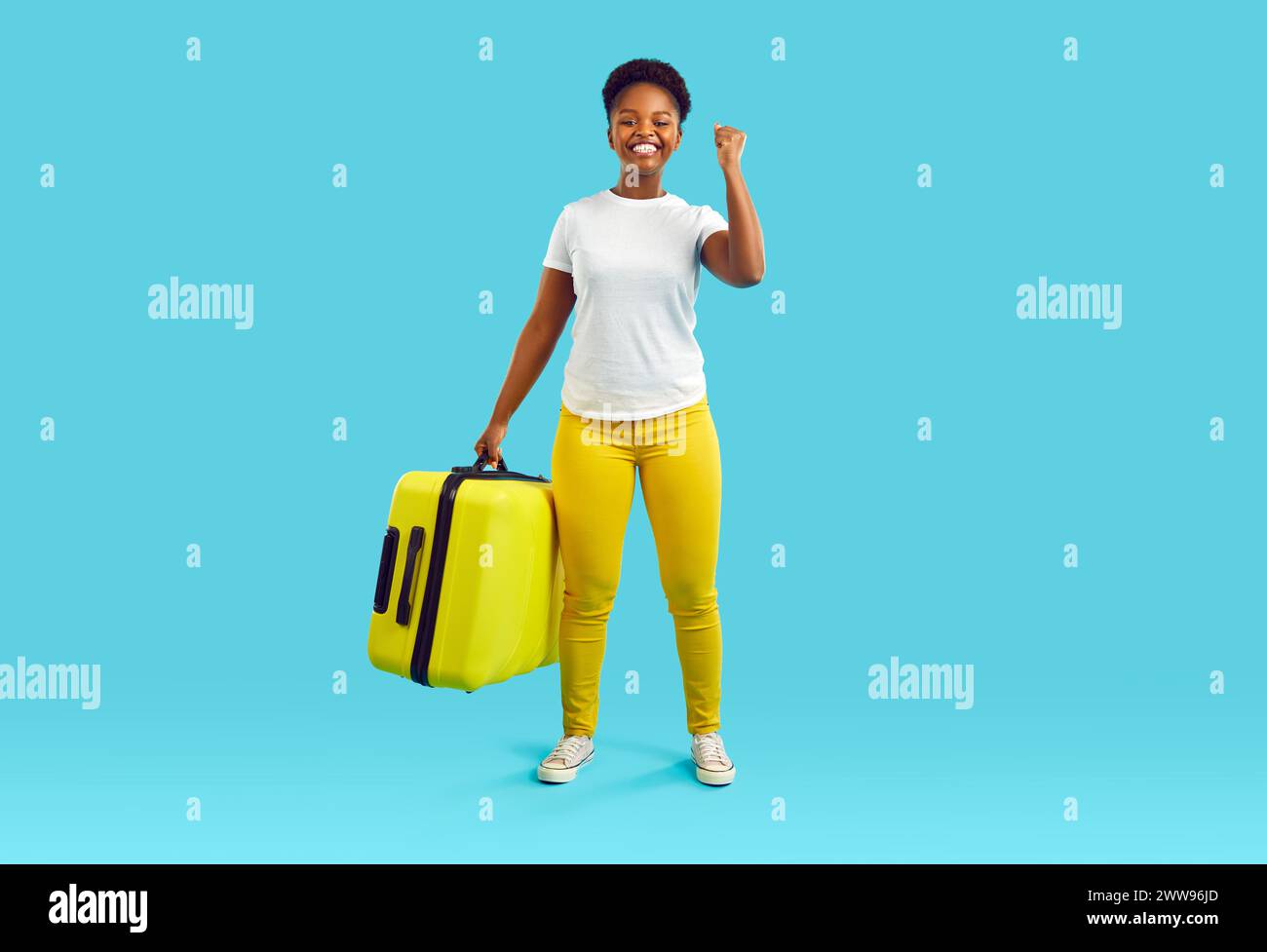 Happy woman carry on huge yellow suitcase on blue background. Lady with ...