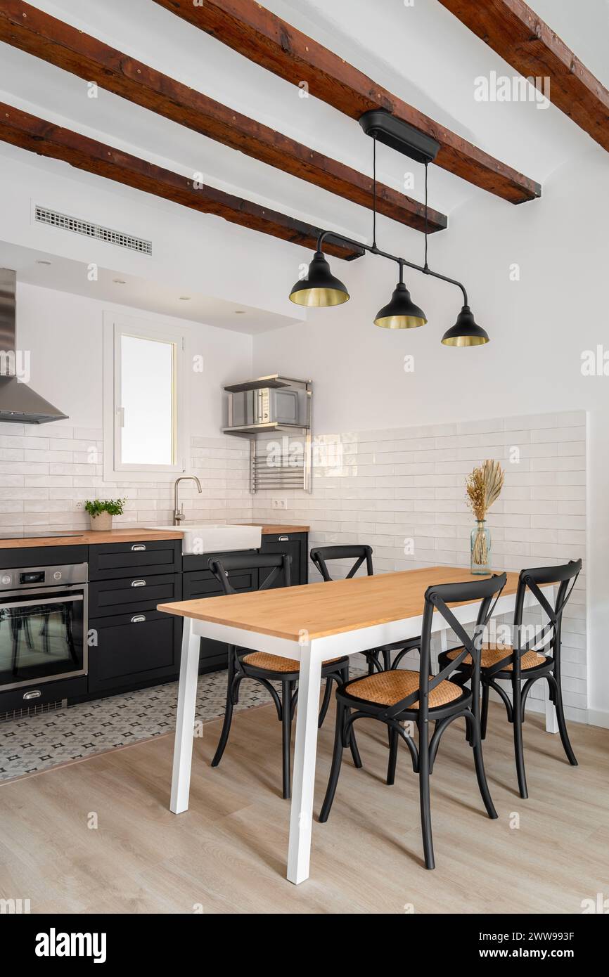 Scandinavian style kitchen with wooden long table and black chairs with ...