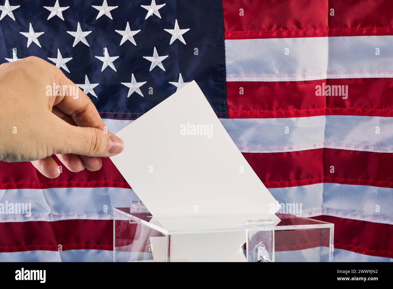 Hand putting his vote into ballot box against national flag of United ...