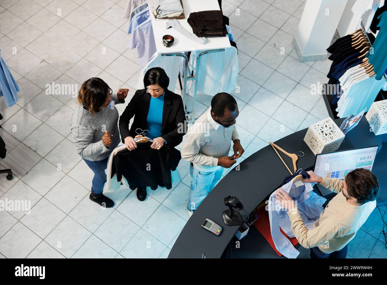 Clothing store customers making purchase and waiting at checkout to ...