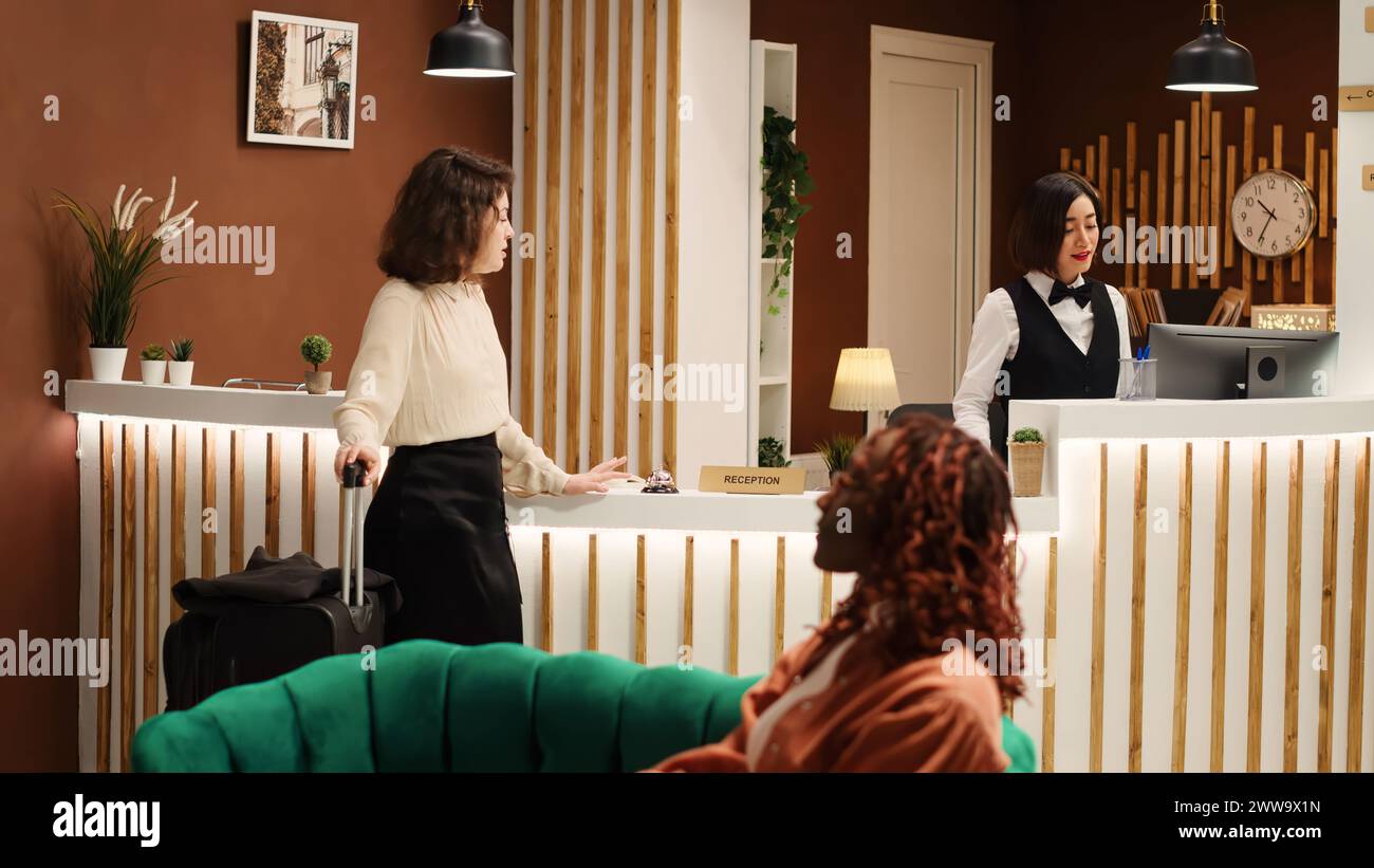 Happy receptionist handing guest room access key card while bellhop ...