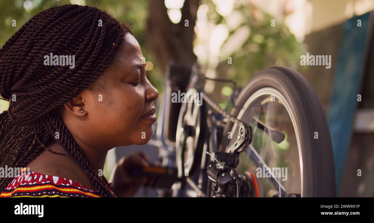 Close-up shot of african american female cyclist lubricating bike chain ...