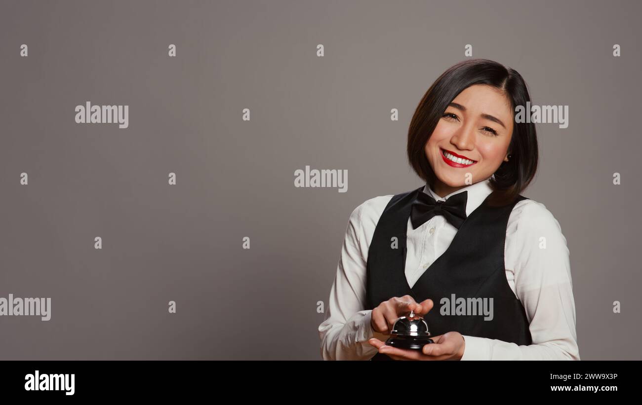 Woman hotel employee ringing front desk service bell in studio, working ...