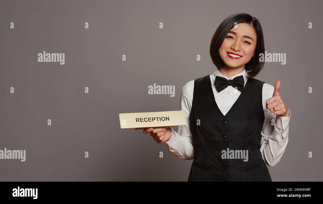 Hotel concierge holding sign to indicate direction for reception desk ...