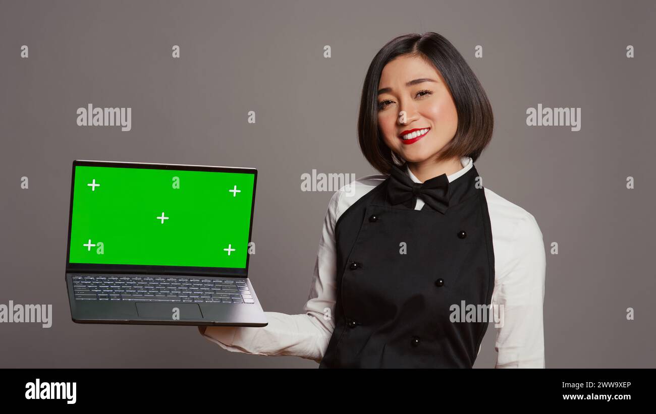 Restaurant employee pointing at greenscreen layout on pc, smiling at ...