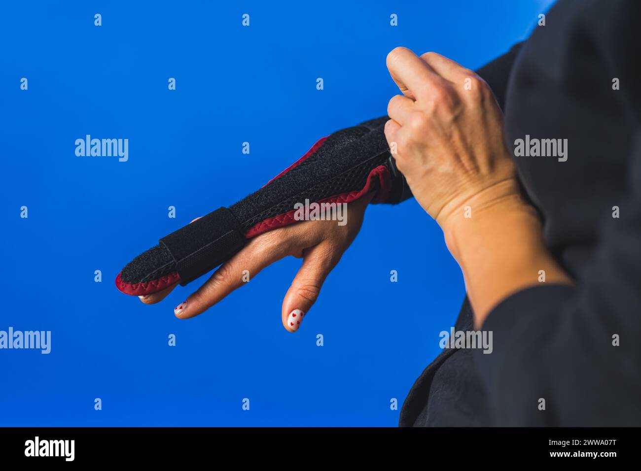 woman adjusting a splint on her middle finger, injured finger blue ...