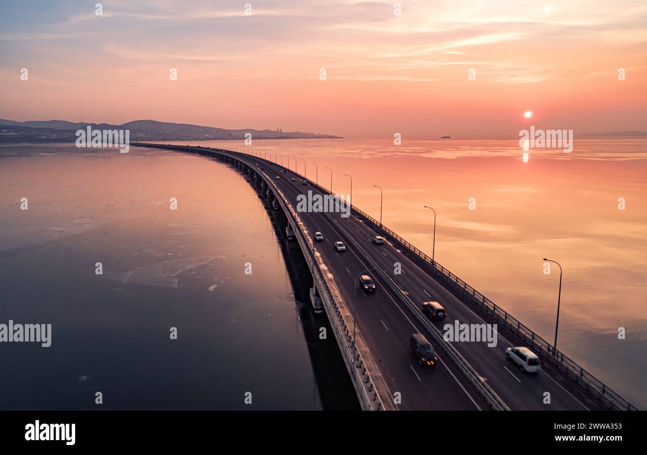 Aerial drone view of low-water bridge across the bay with moving car ...
