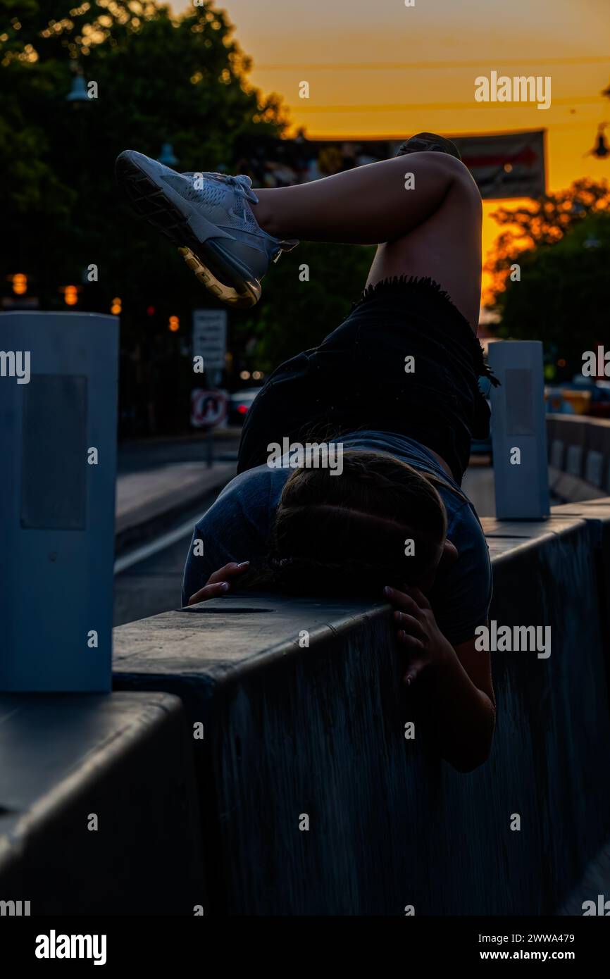 An individual performing a handstand against a sunset backdrop ...
