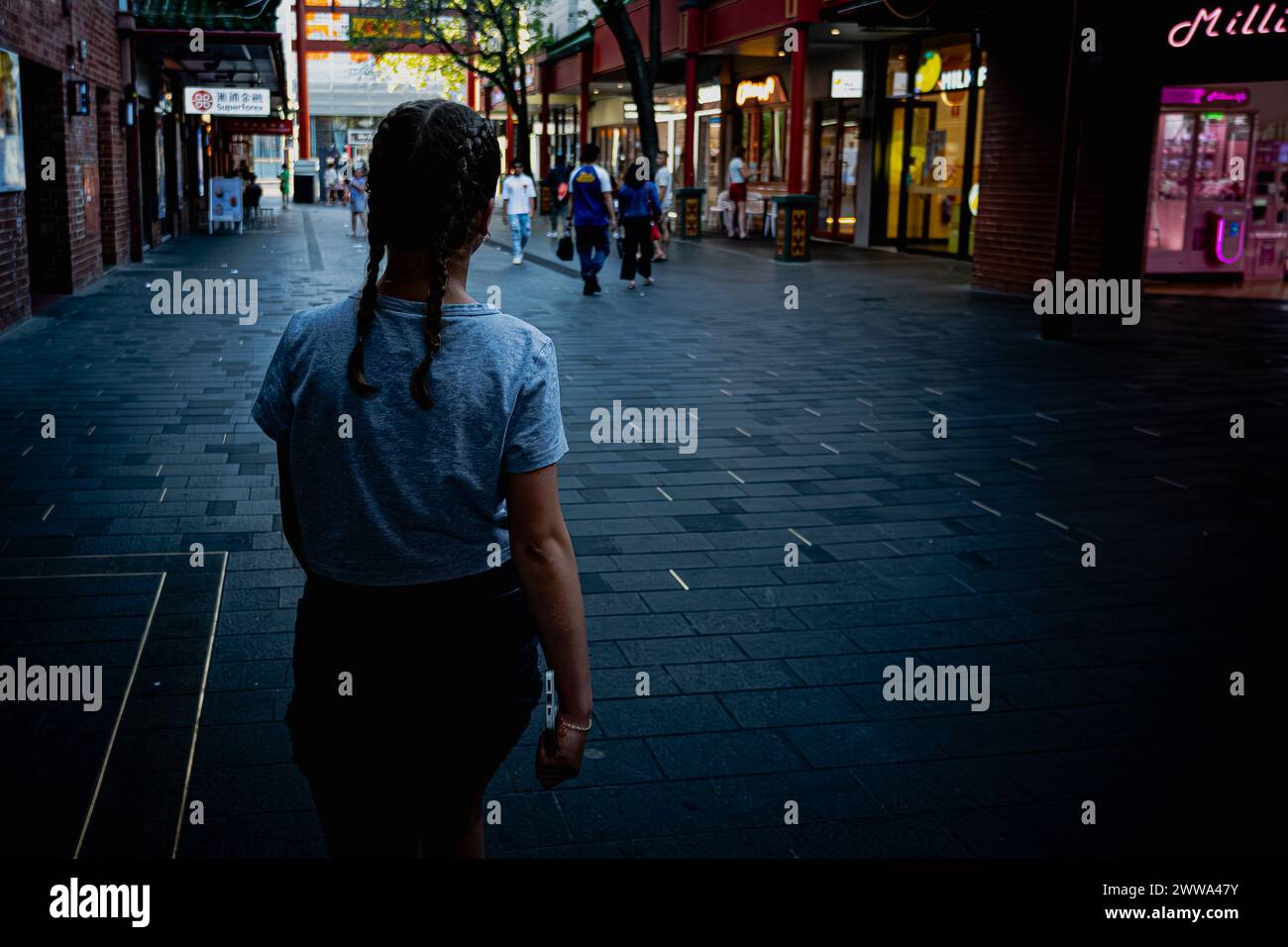 A person walks through a shaded alley, with light casting down the ...