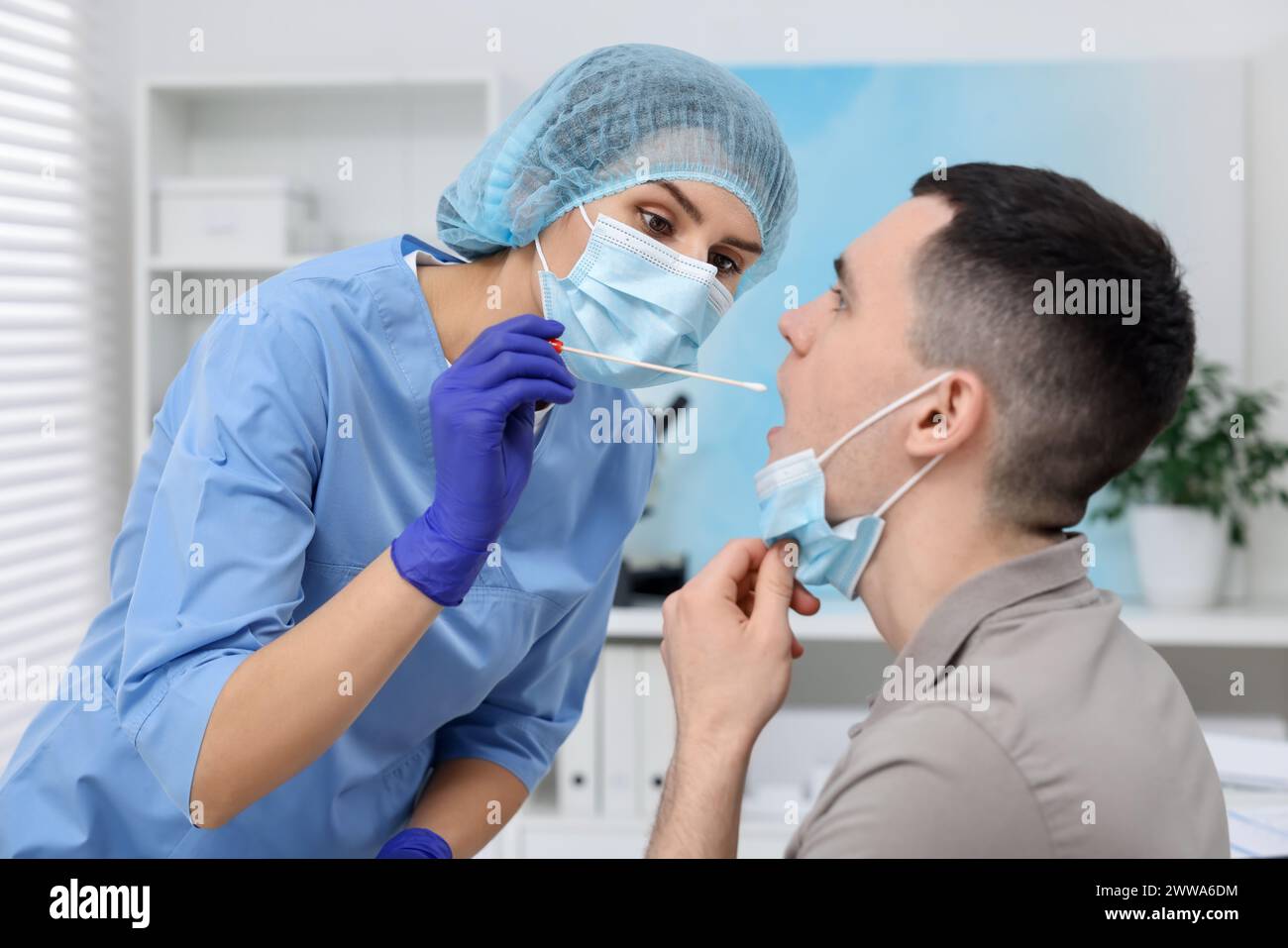 Laboratory testing. Doctor taking sample from patient's mouth with ...