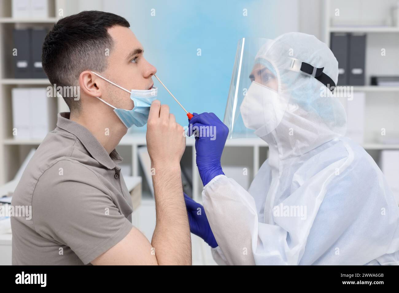 Laboratory testing. Doctor in uniform taking sample from patient's nose ...
