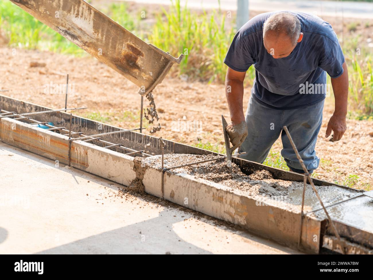 Using trowel worker plasters wet concrete cement wheel stop after it ...
