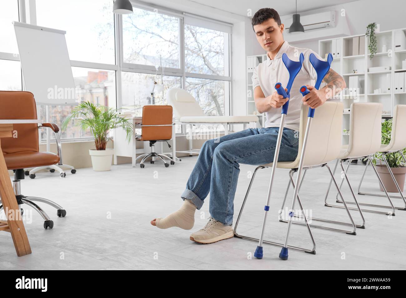 Injured young man after accident with crutches sitting in clinic Stock ...