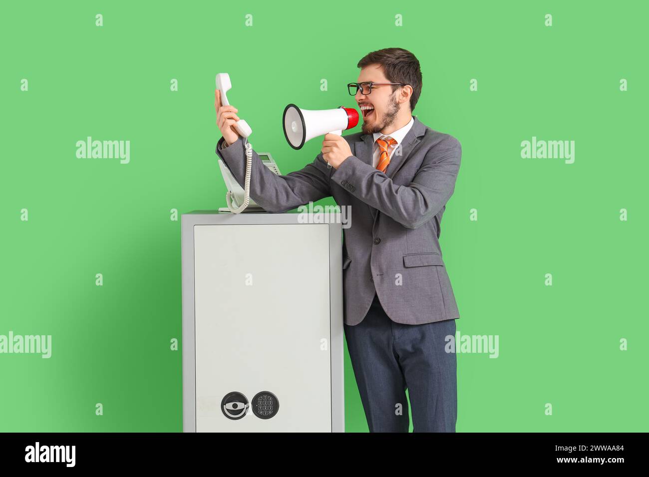 Happy young man with safe box talking by phone and screaming near green ...
