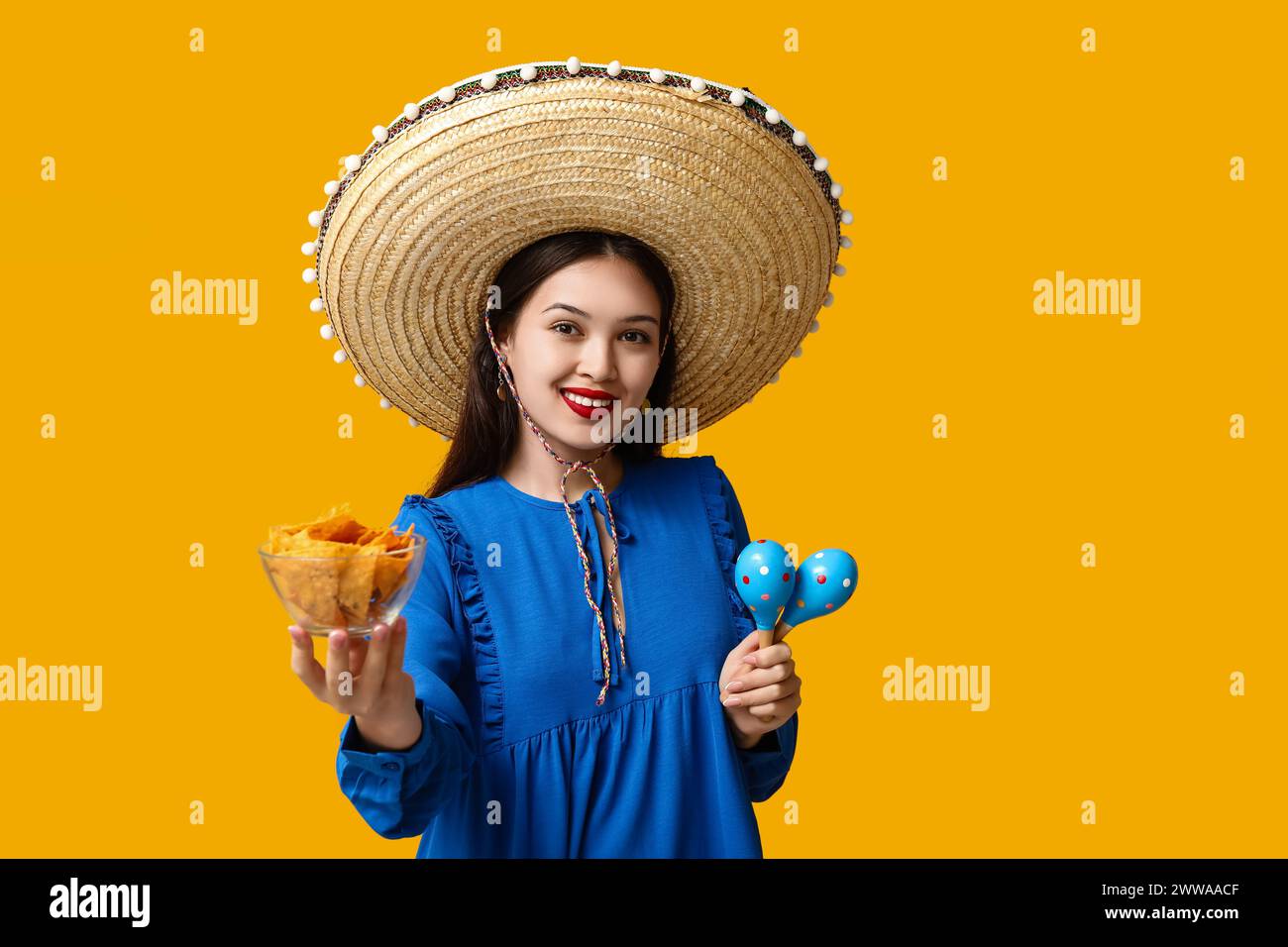Portrait of young woman with sombrero, maracas and tortilla chips on ...