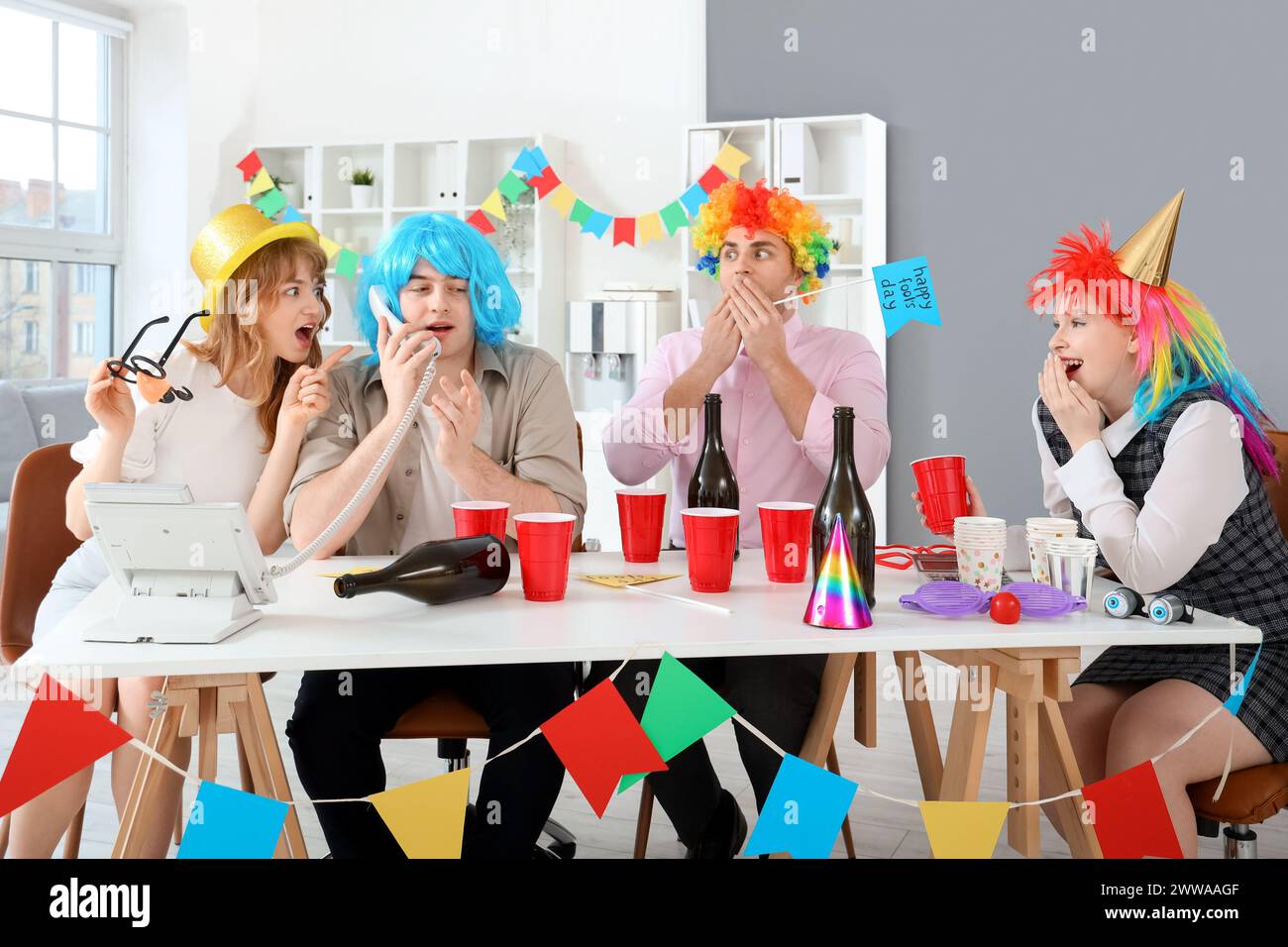 Business colleagues playing prank on telephone at office party. April ...
