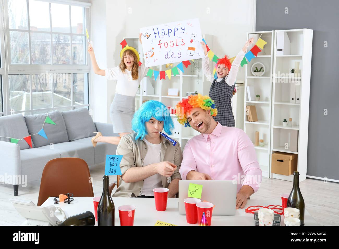 Business colleagues with poster and laptop celebrating April Fools' Day ...