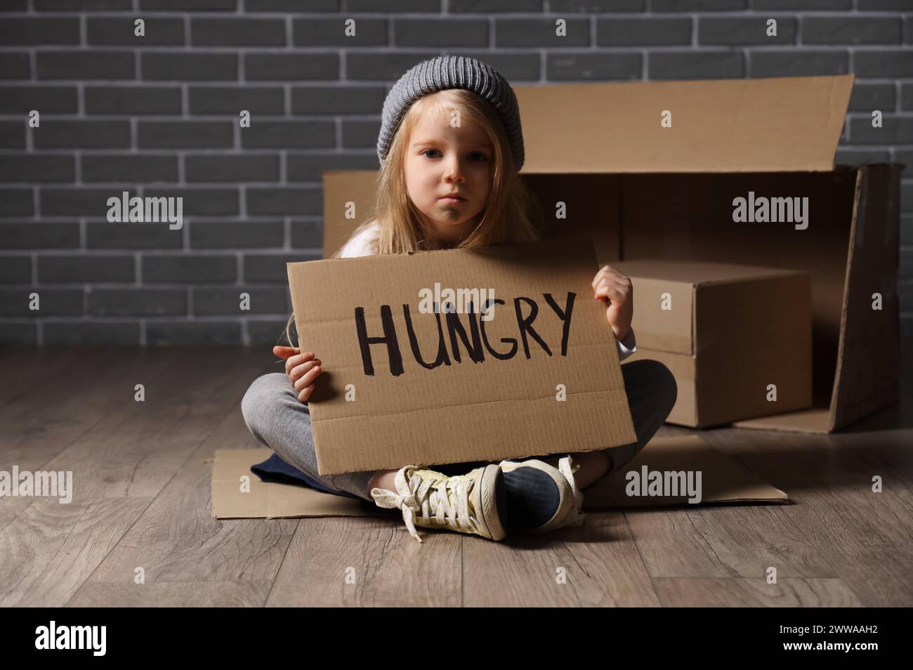 Homeless little girl begging for food near grey brick wall Stock Photo ...