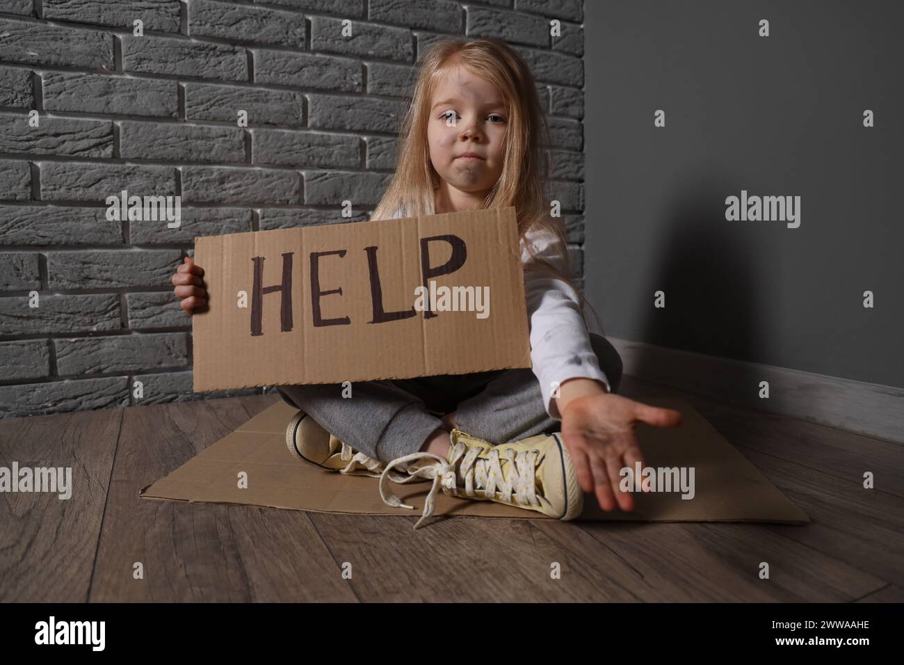 Homeless little girl begging for help near grey brick wall Stock Photo ...