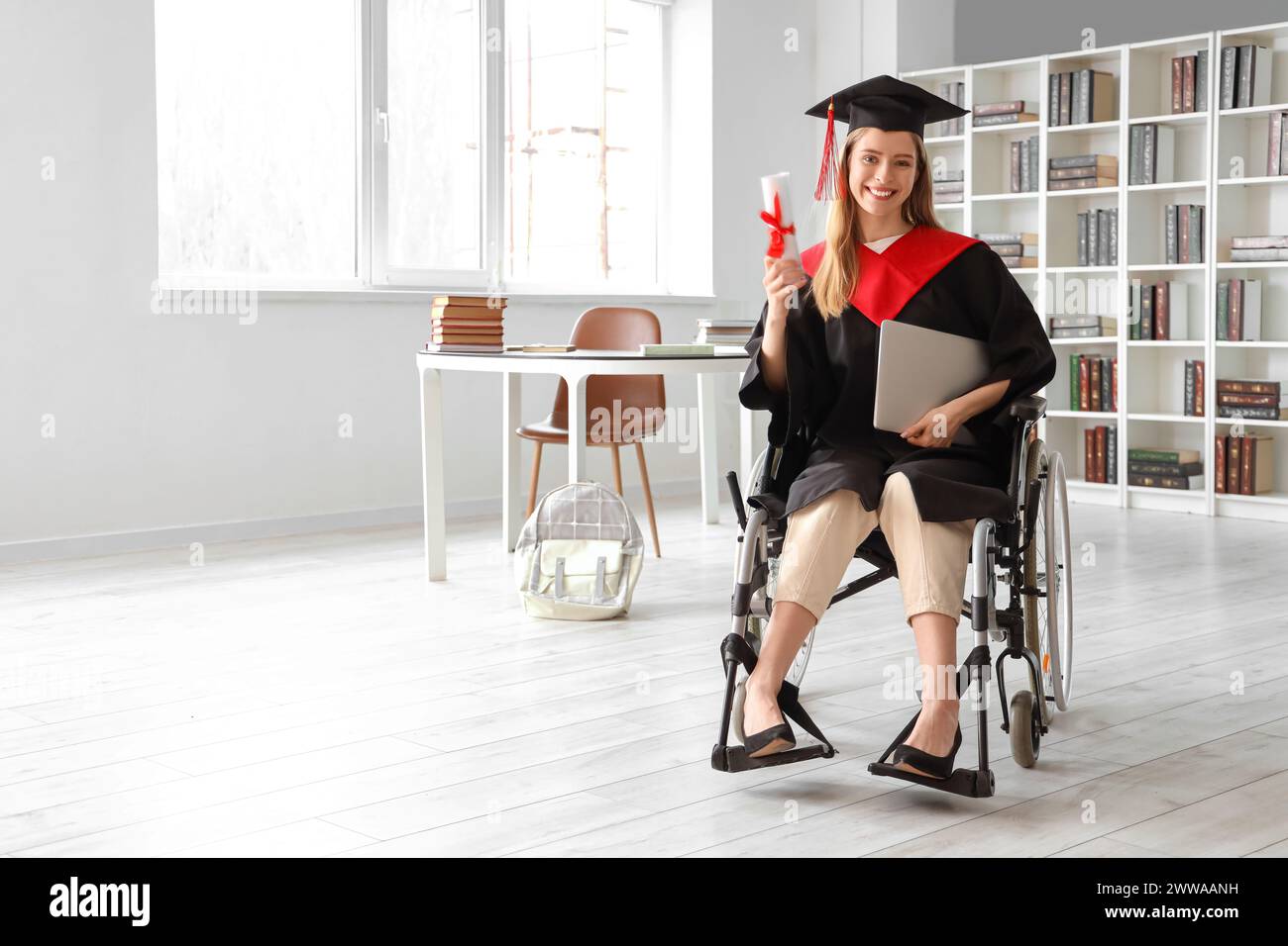 Female graduate in wheelchair with laptop and diploma at university ...