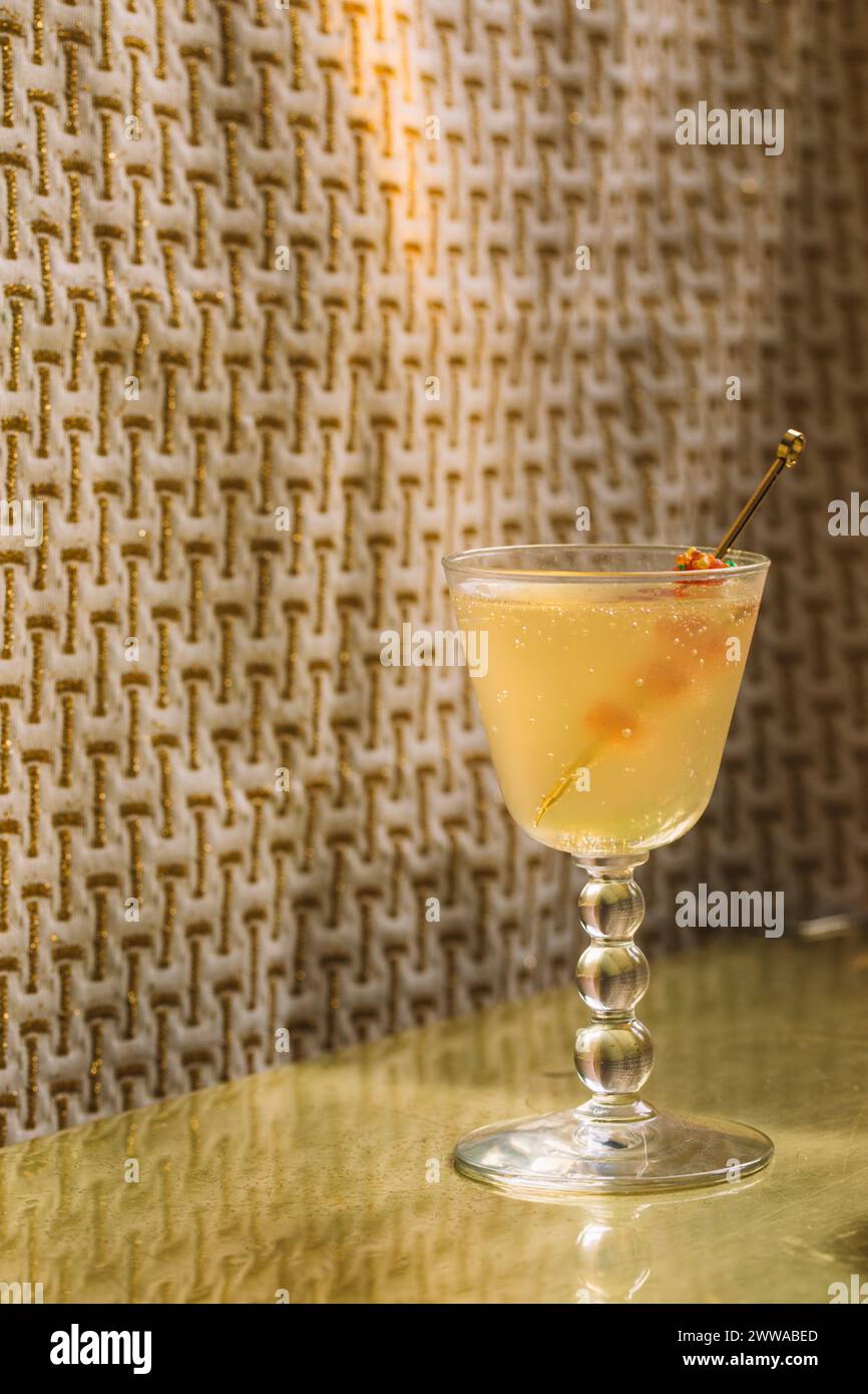 bubbly yellow cocktail with gummy cluster candy on cocktail pick ...