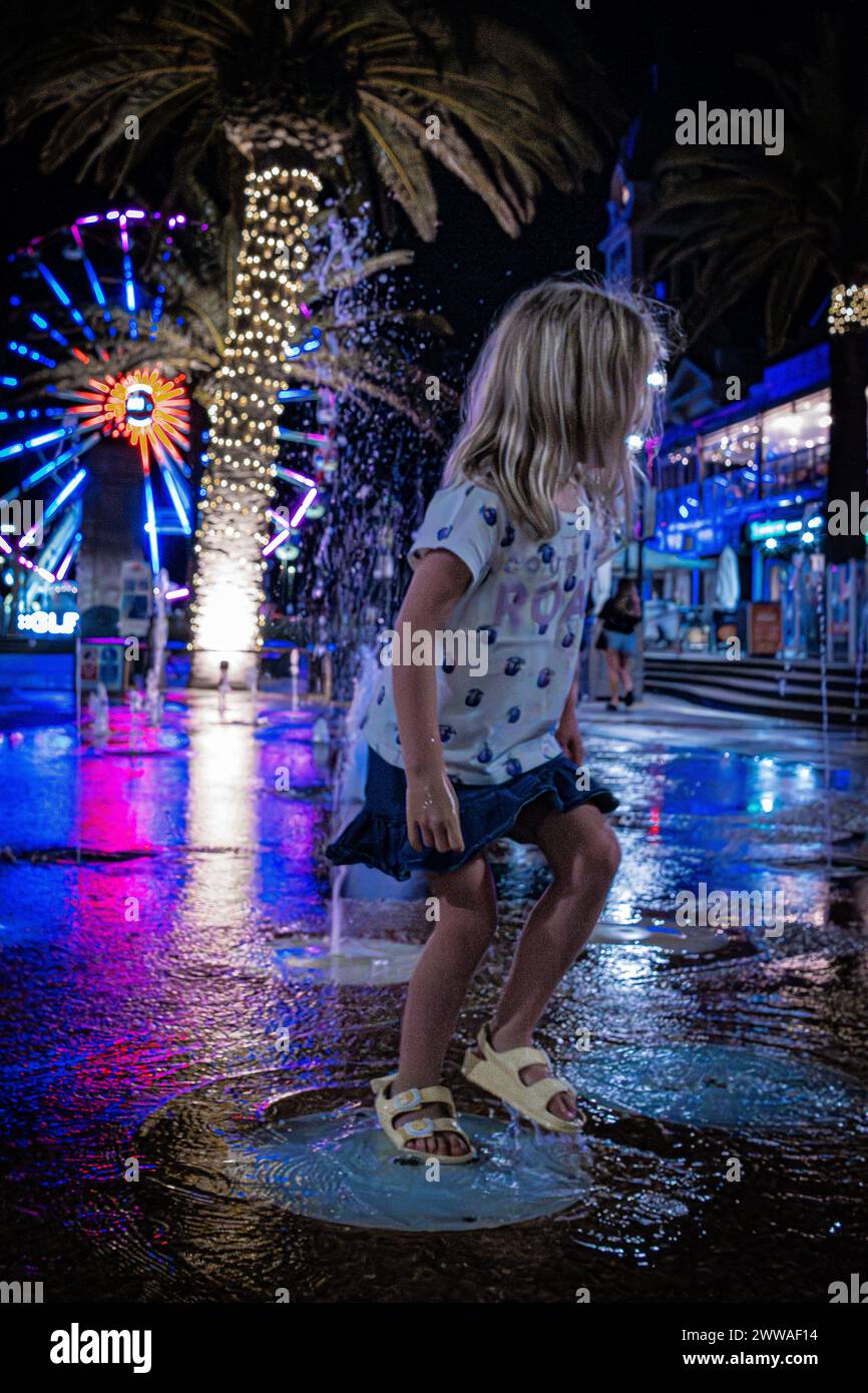 A child splashing water on a colorful urban splash pad at night Stock ...