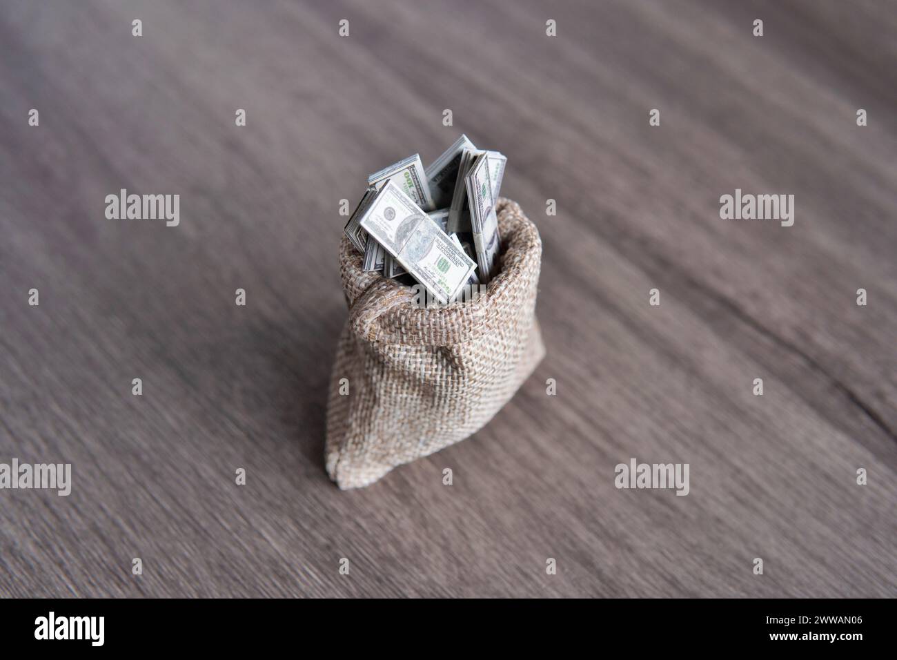 Closeup image of burlap sack overflowing with stacks of U.S. dollar ...