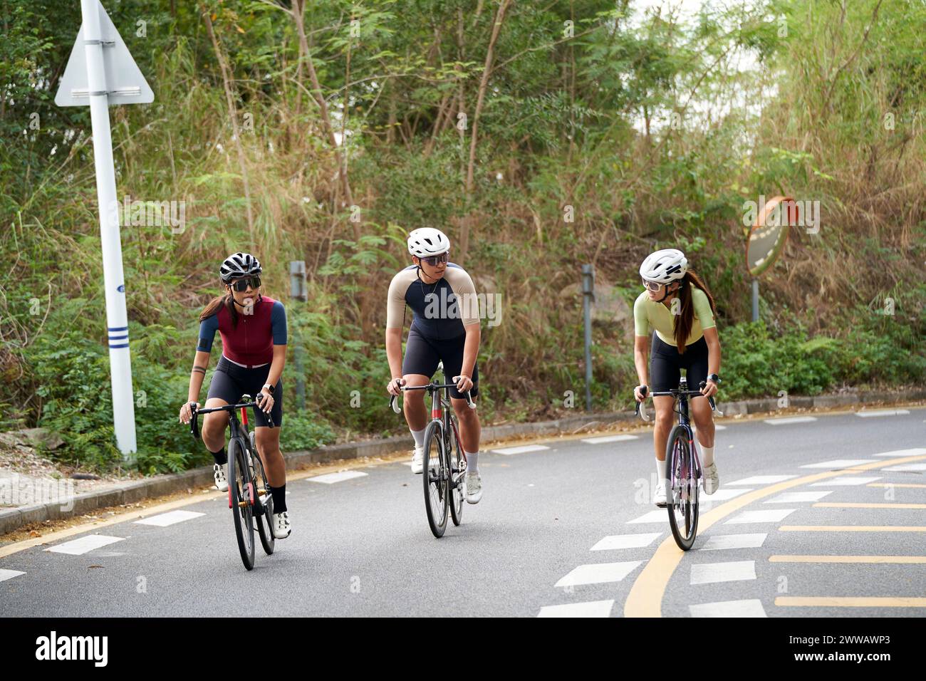 three young asian cyclists riding bike outdoors on rural road Stock ...