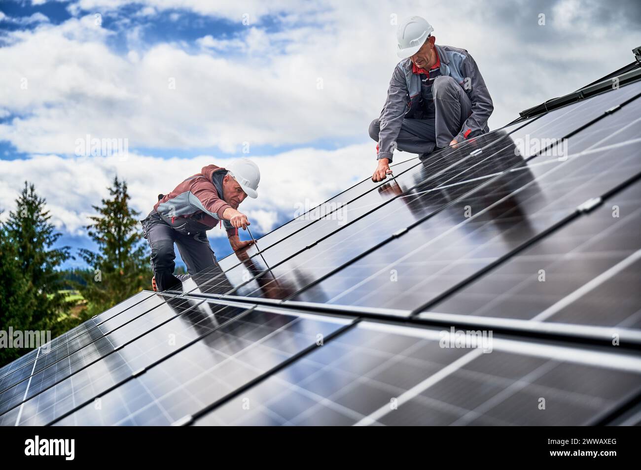 Electricians installing photovoltaic solar panels on roof of house. Men ...