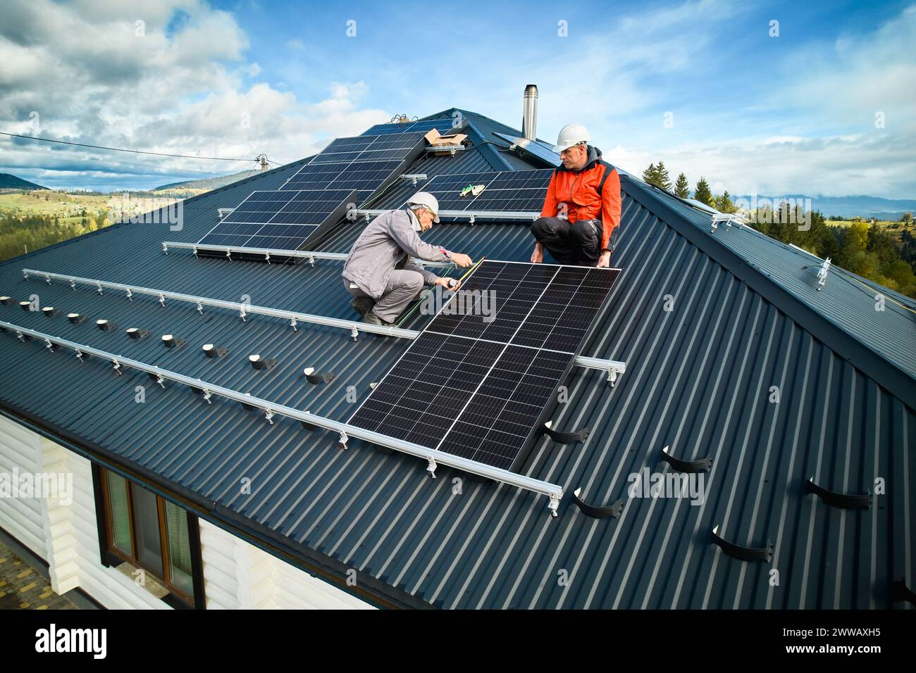 Male technicians adjusting the solar panel on roof of house. Solar ...