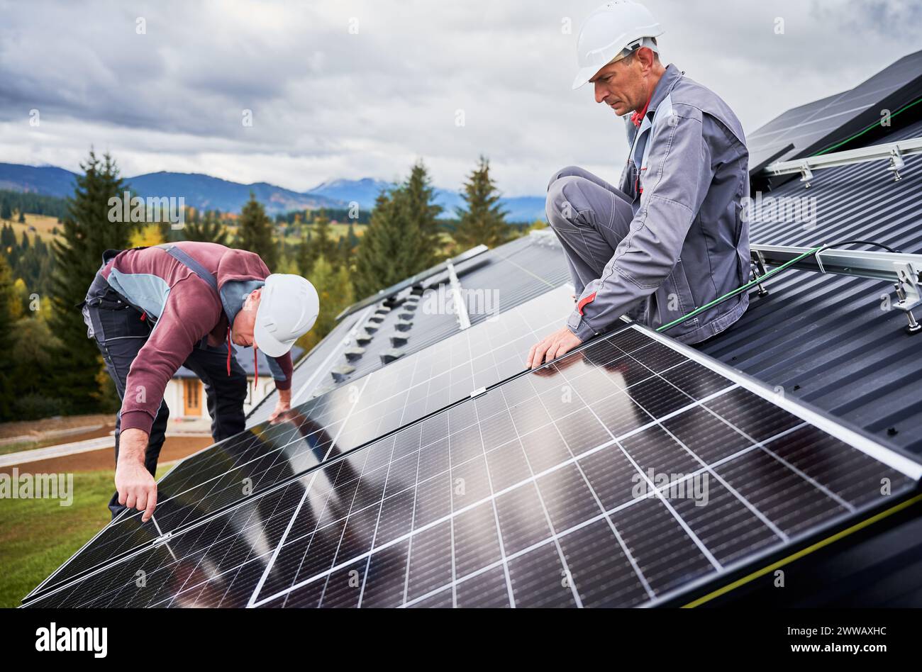Electricians installing photovoltaic solar panels on roof of house. Men ...