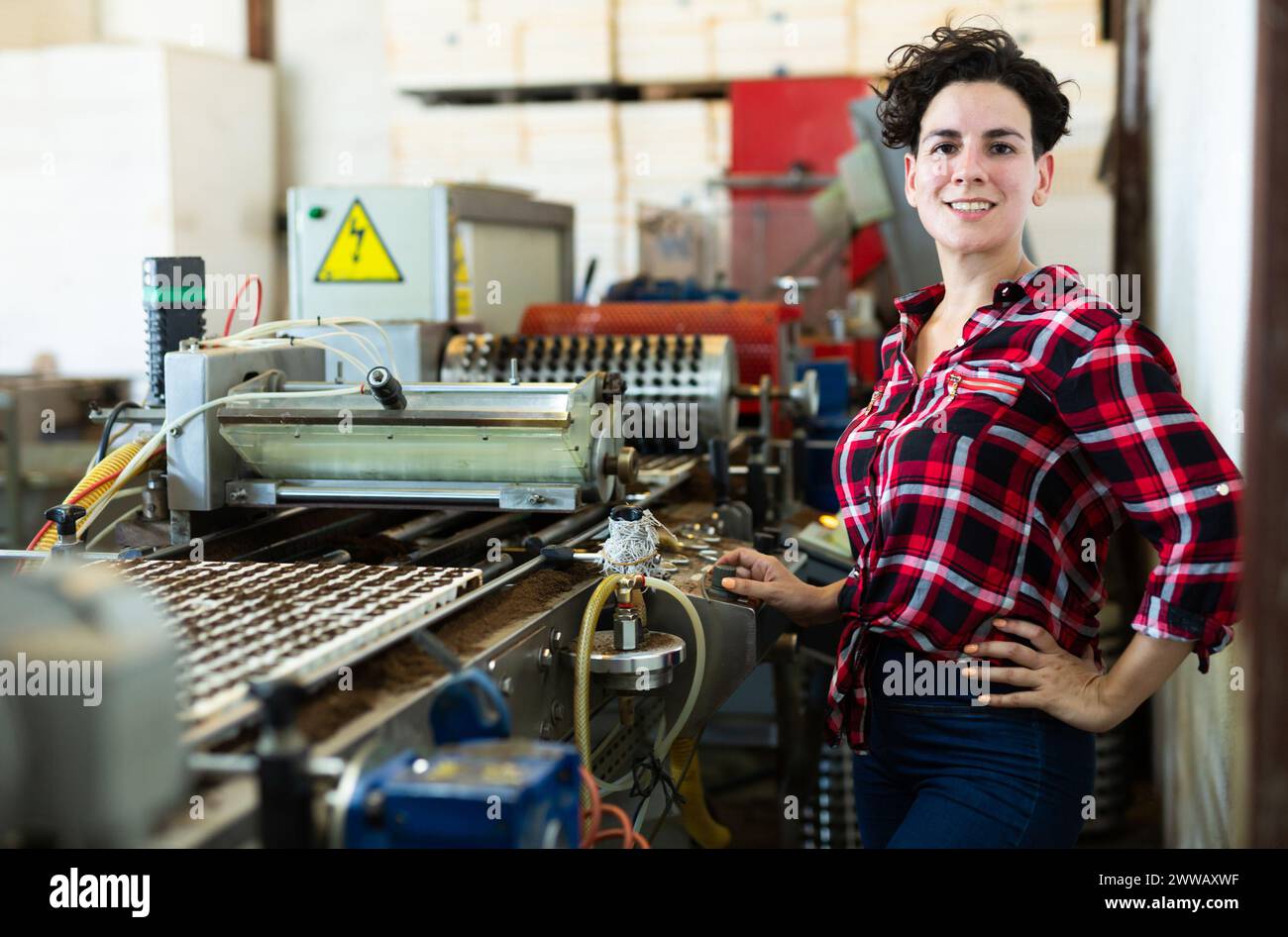 Confident woman machine operator working with automatic conveyor ...