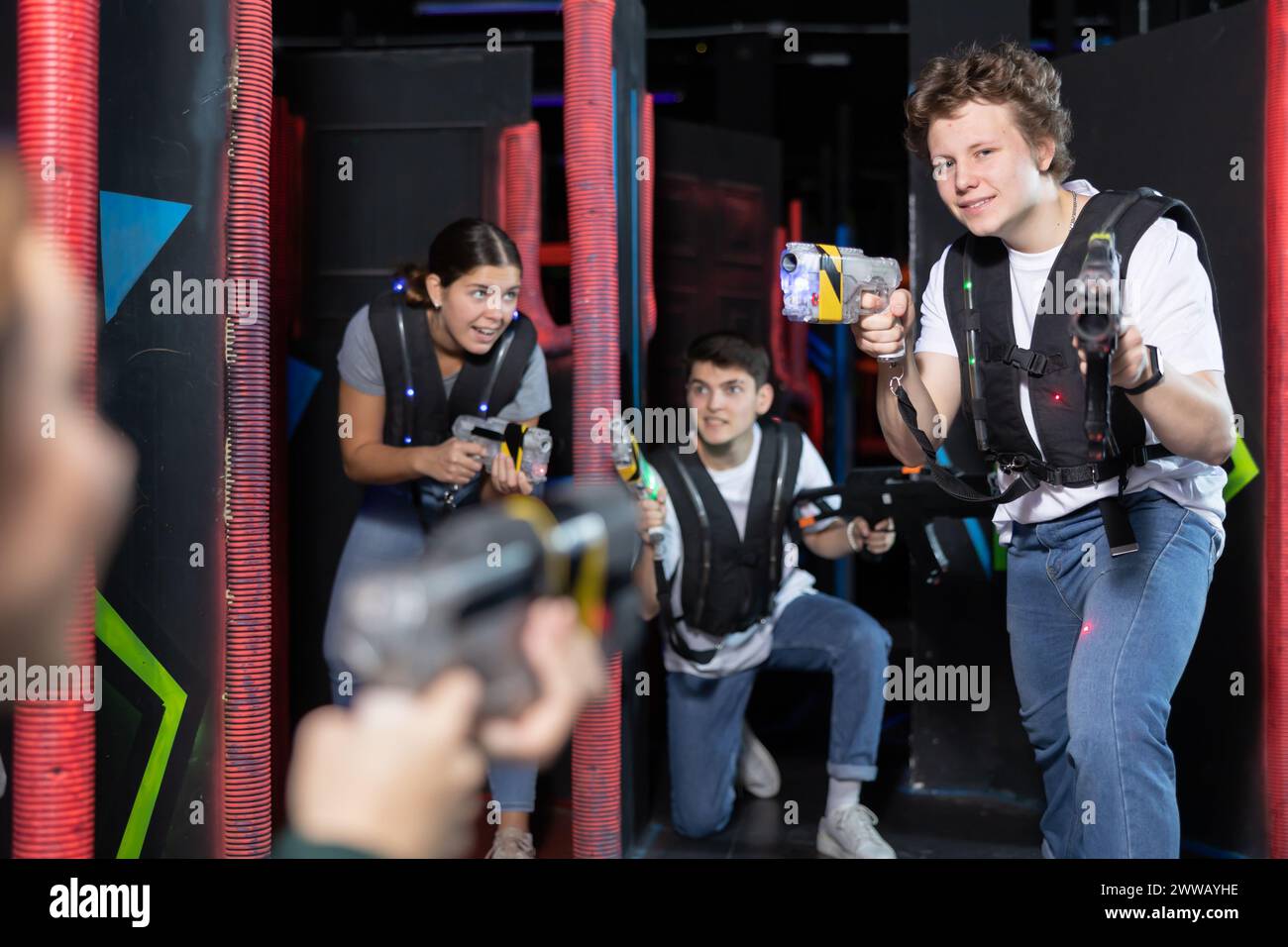 Emotional man with laser pistol playing laser tag with friends on dark ...