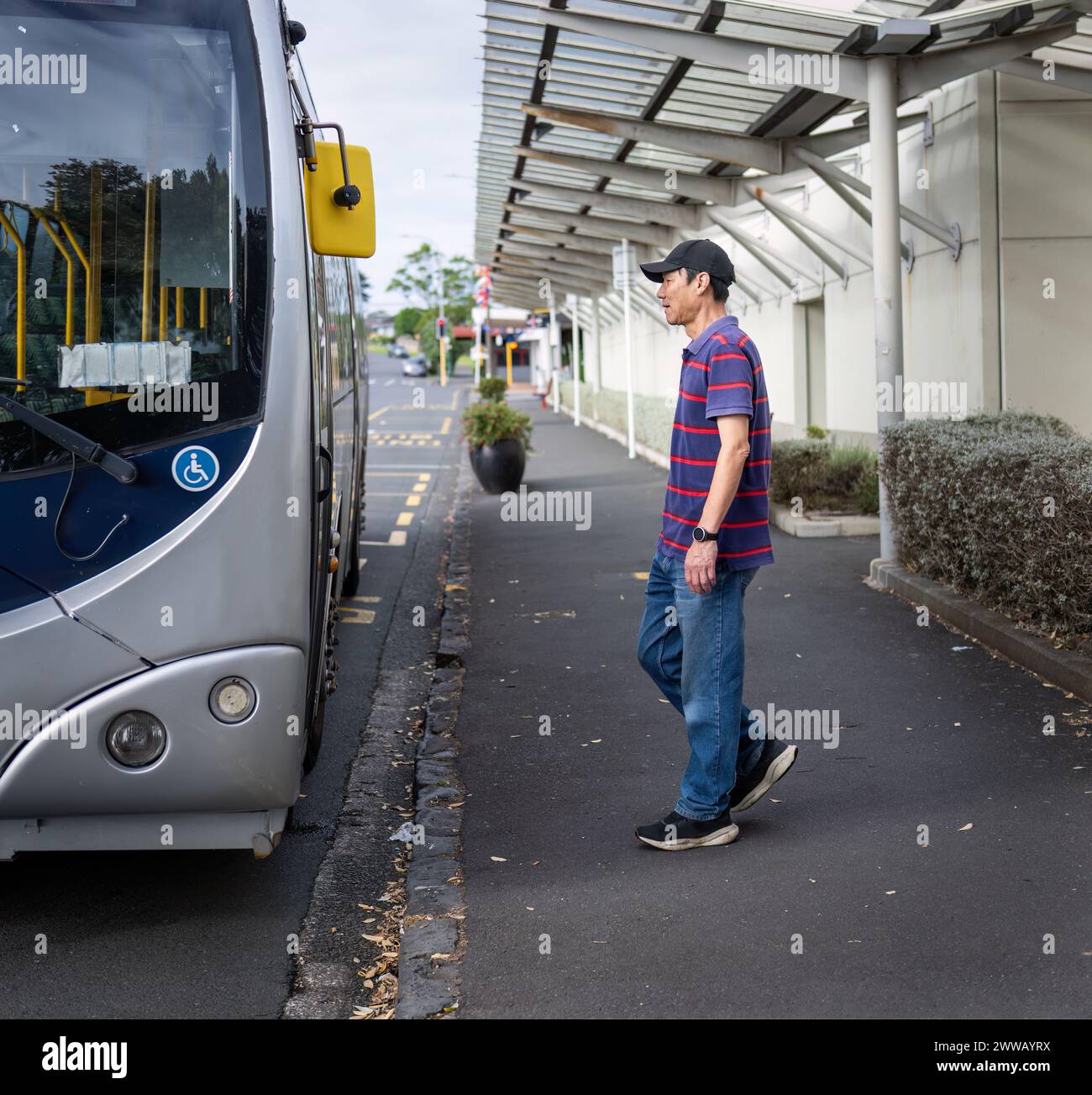 Man smiling and walking to the bus stop on a city road. Auckland Stock ...