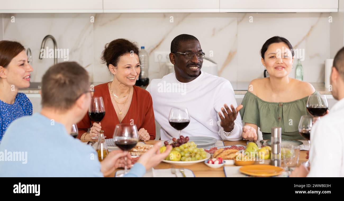 Friends sharing laughter and conversation over dinner at home Stock ...