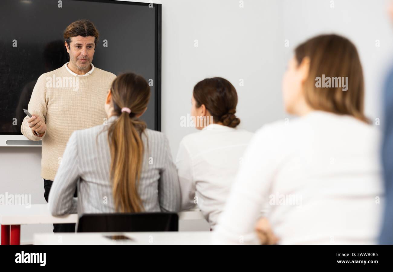 Experienced male teacher giving lecture to group of student Stock Photo ...